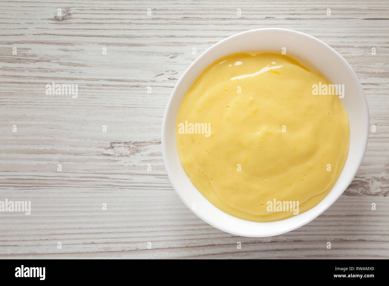Homemade vanilla custard pudding on a white wooden table. Overhead ...