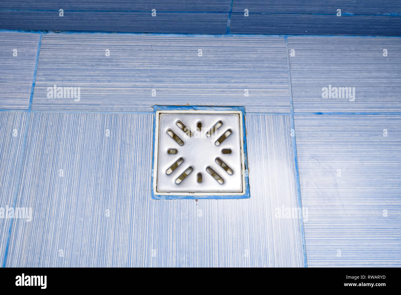 Close-up view of blue tiles in bathroom and stainless steel metal drain ...