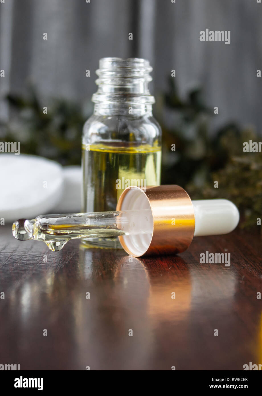 Essential oil dripping from a glass dropper on a dark table Stock Photo ...