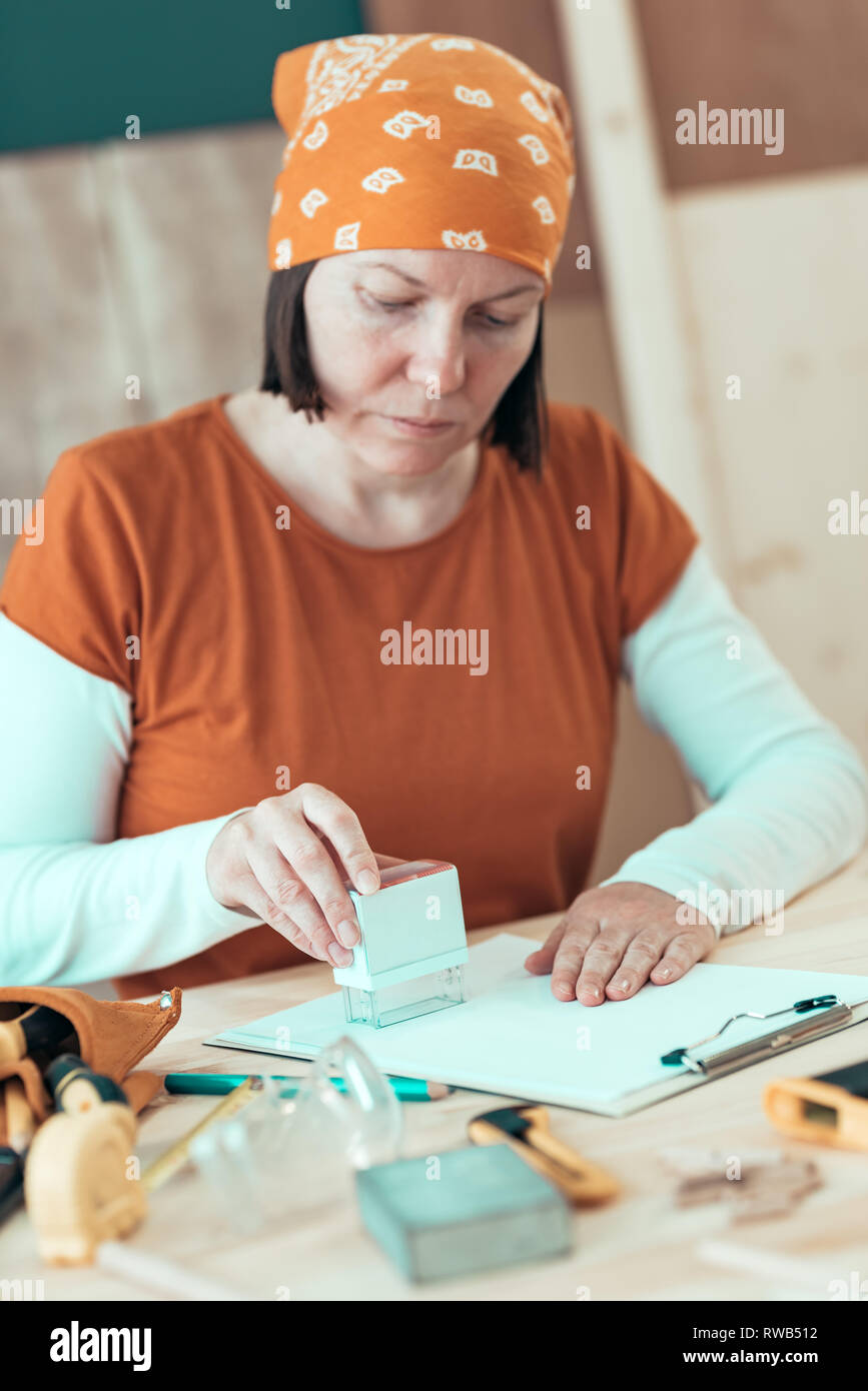 Self employed female carpenter is stamping project documentation in ...