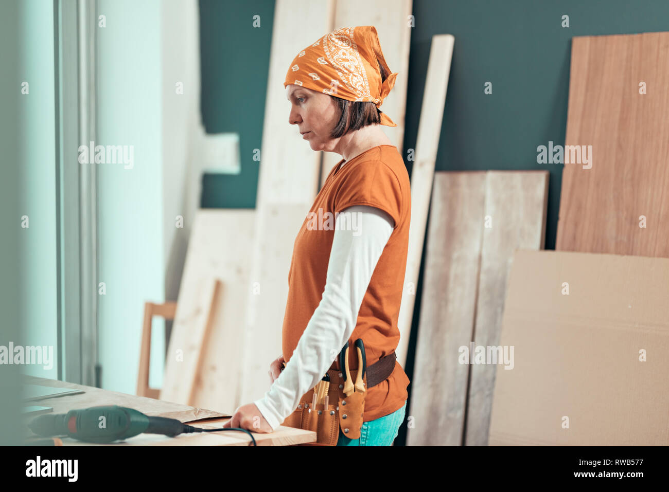 Serious female carpenter thinking about project in woodwork workshop ...