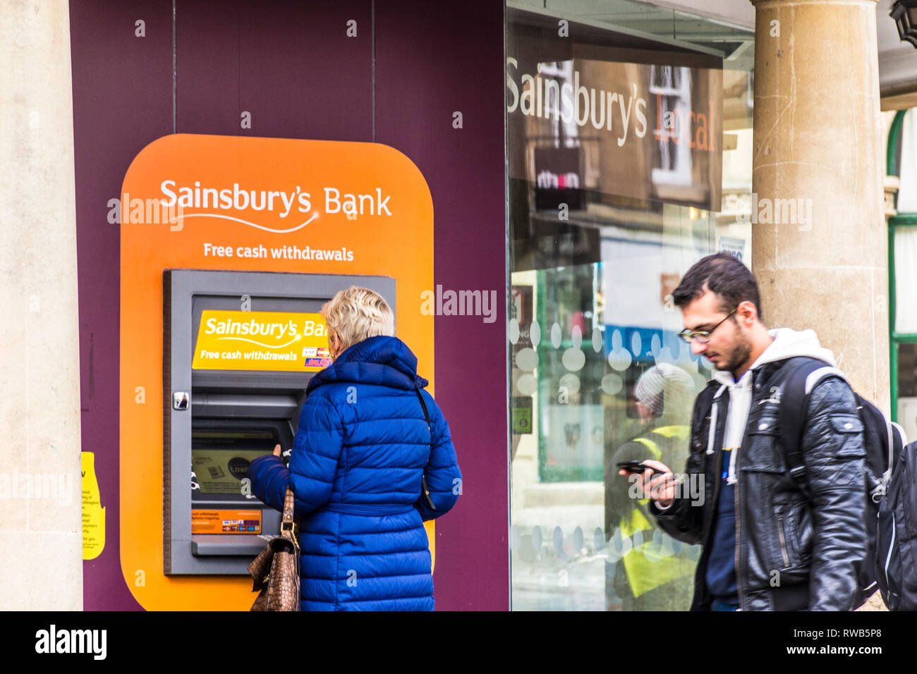 Woman using ATM at Sainsburys bank in Bath, Somerset, UK Stock Photo ...