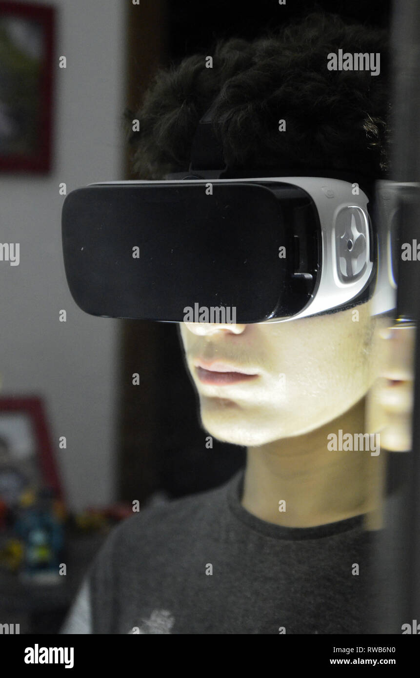 A young Caucasian boy wears the VR 360 viewer in his room, the virtual ...