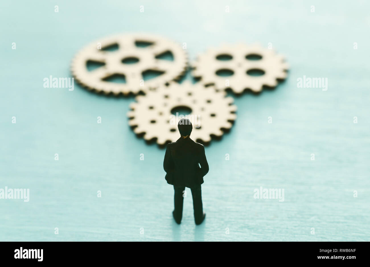 Miniature people looking at cogwheel in set of gears mechanism. Problem ...