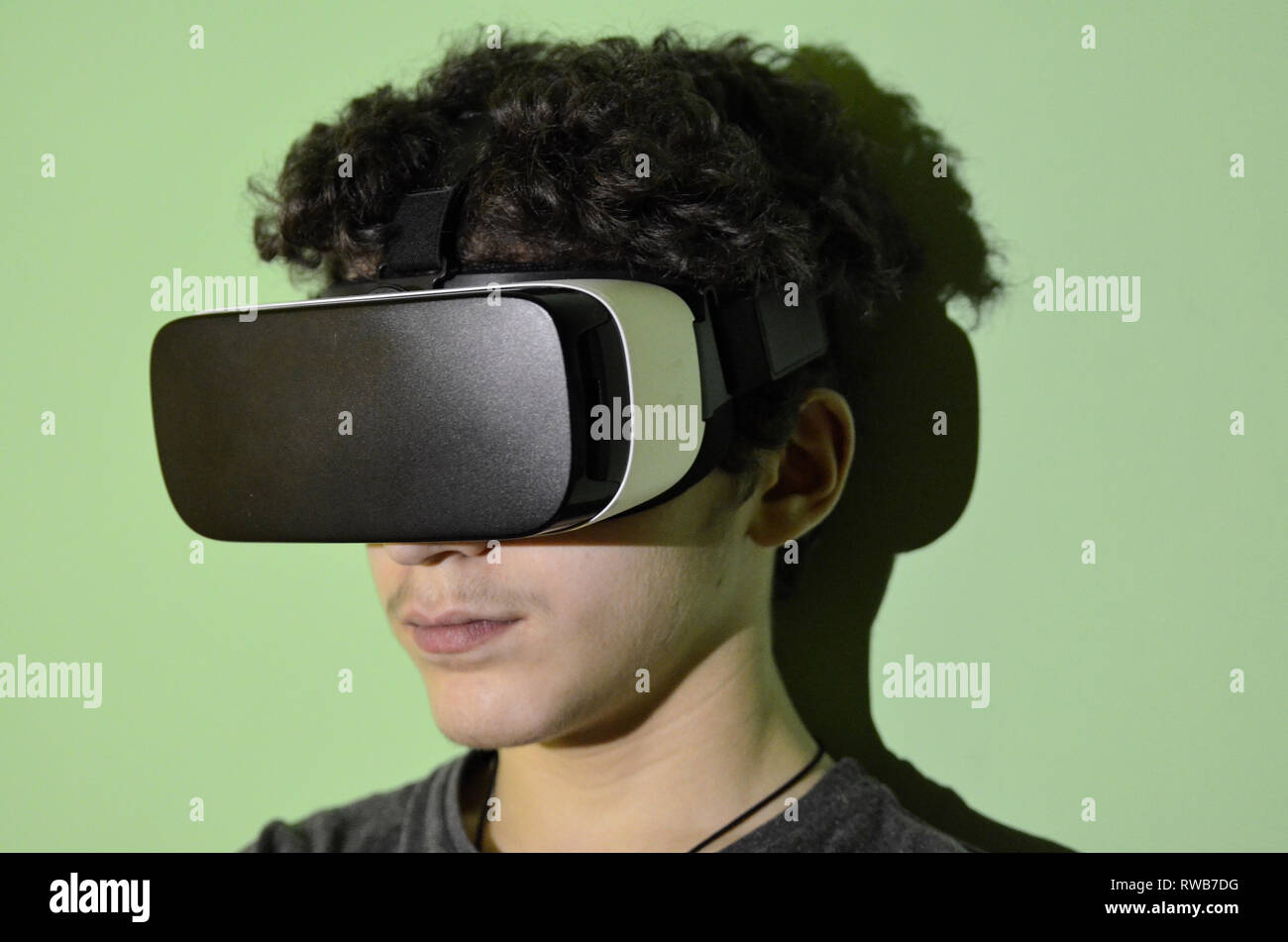 A young Caucasian boy wears the VR 360 viewer in his room, the virtual ...
