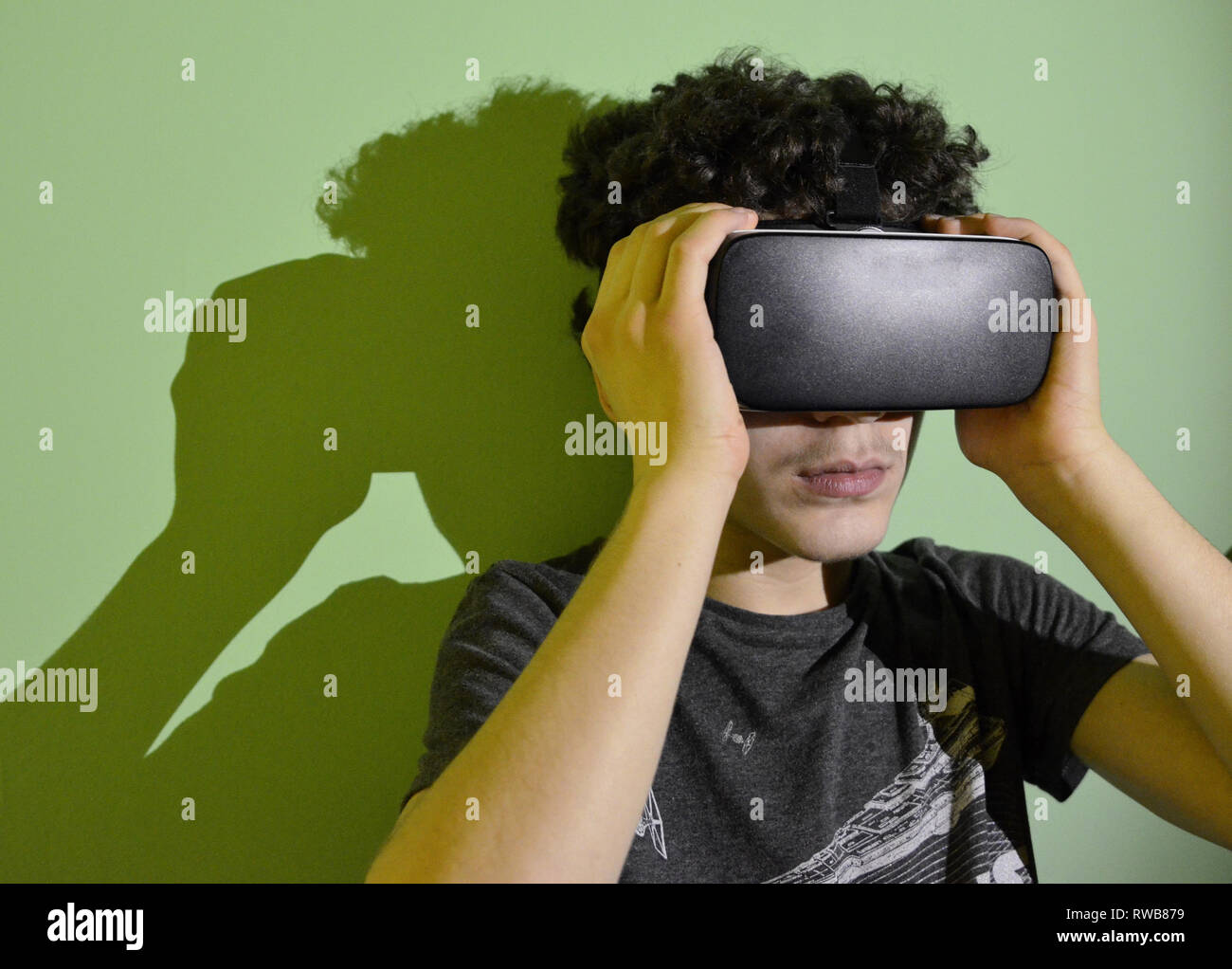 A young Caucasian boy wears the VR 360 viewer in his room, the virtual ...
