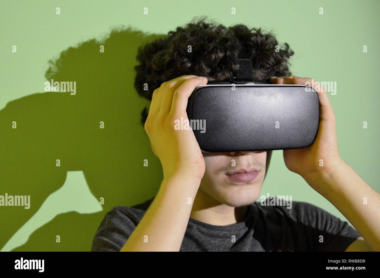 A young Caucasian boy wears the VR 360 viewer in his room, the virtual ...