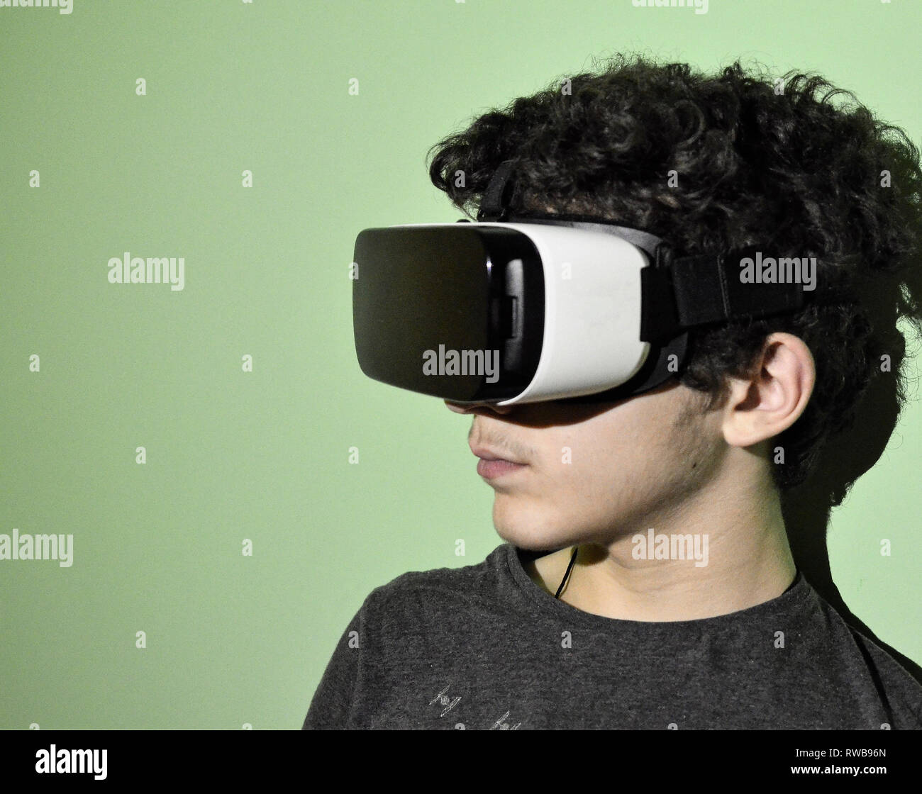 A young Caucasian boy wears the VR 360 viewer in his room, the virtual ...