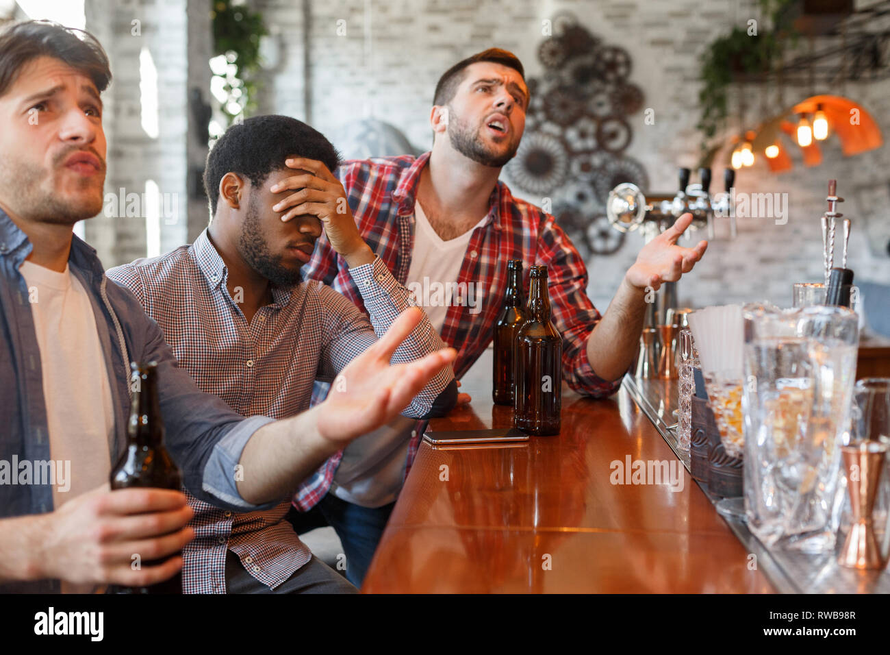 Lost match. Upset friends watching football in sport bar Stock Photo ...