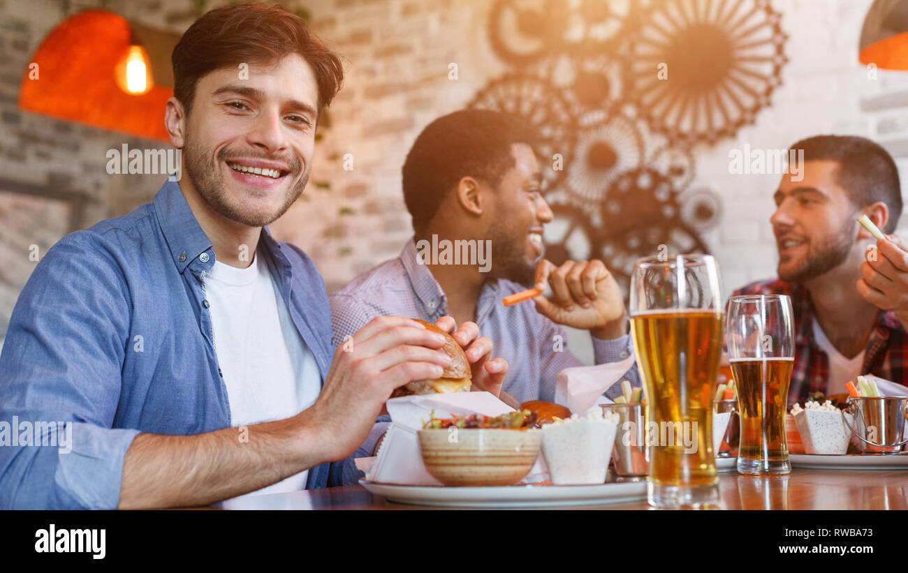 Meeting in pub. Friends eating burgers and drinking beer Stock Photo ...