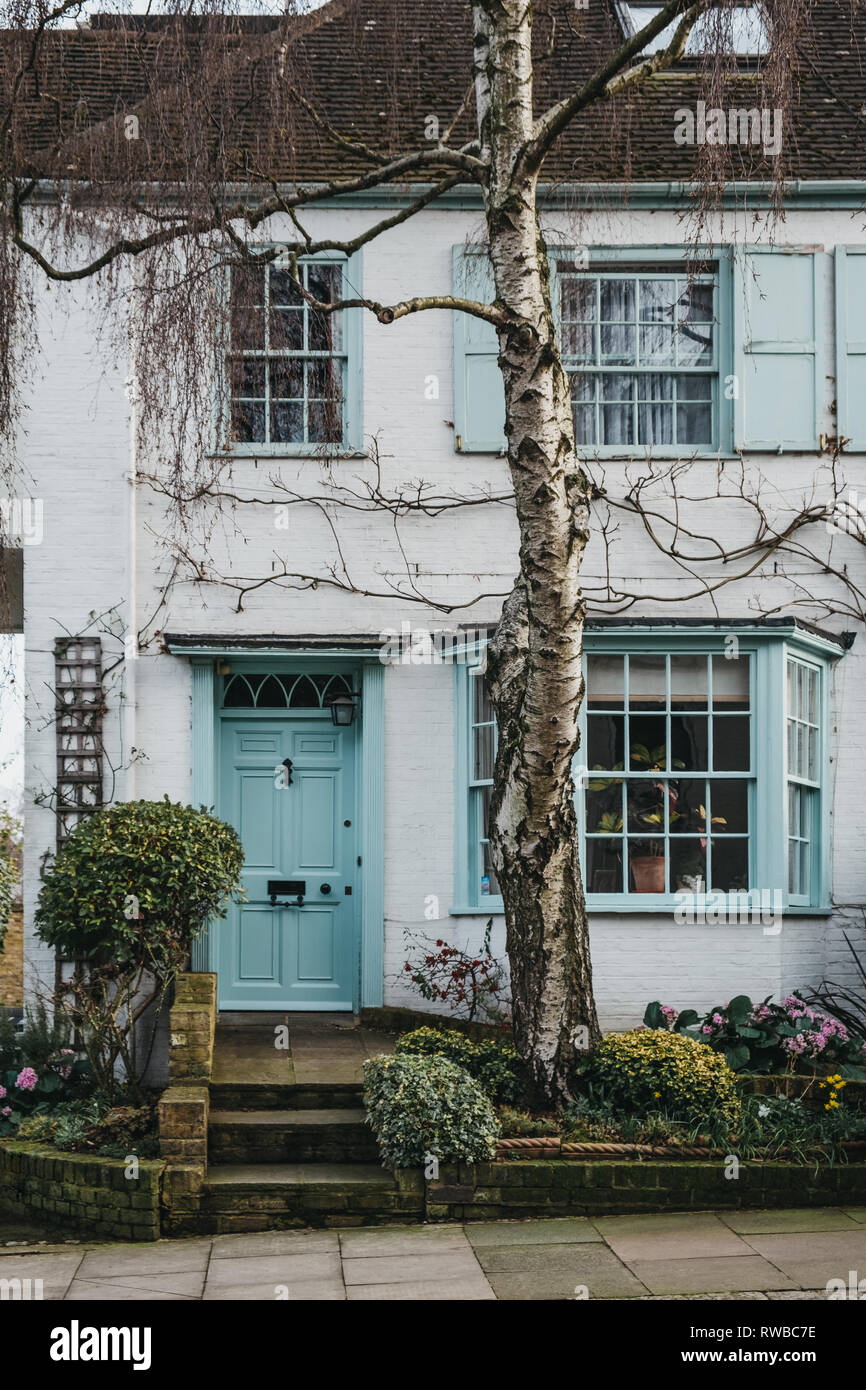 Colourful turquoise door and trim on a facade of traditional English ...