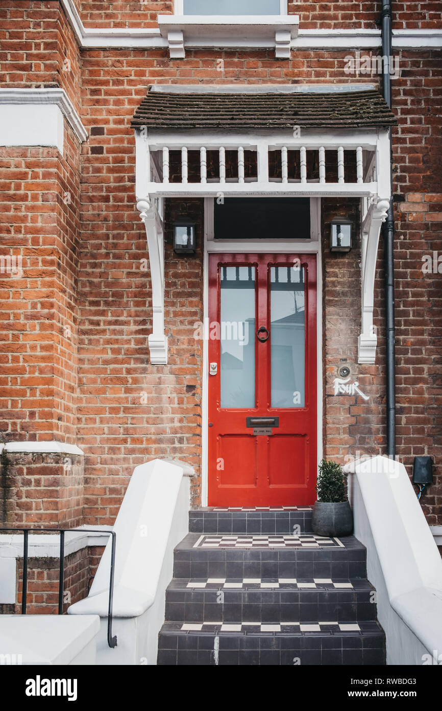 Colourful bright red door on a facade of traditional English house in ...