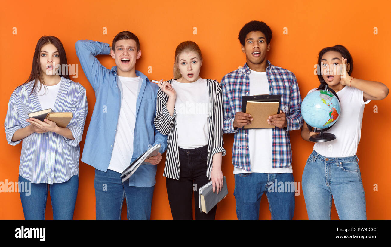 Surprised classmates with books looking at camera over background Stock ...