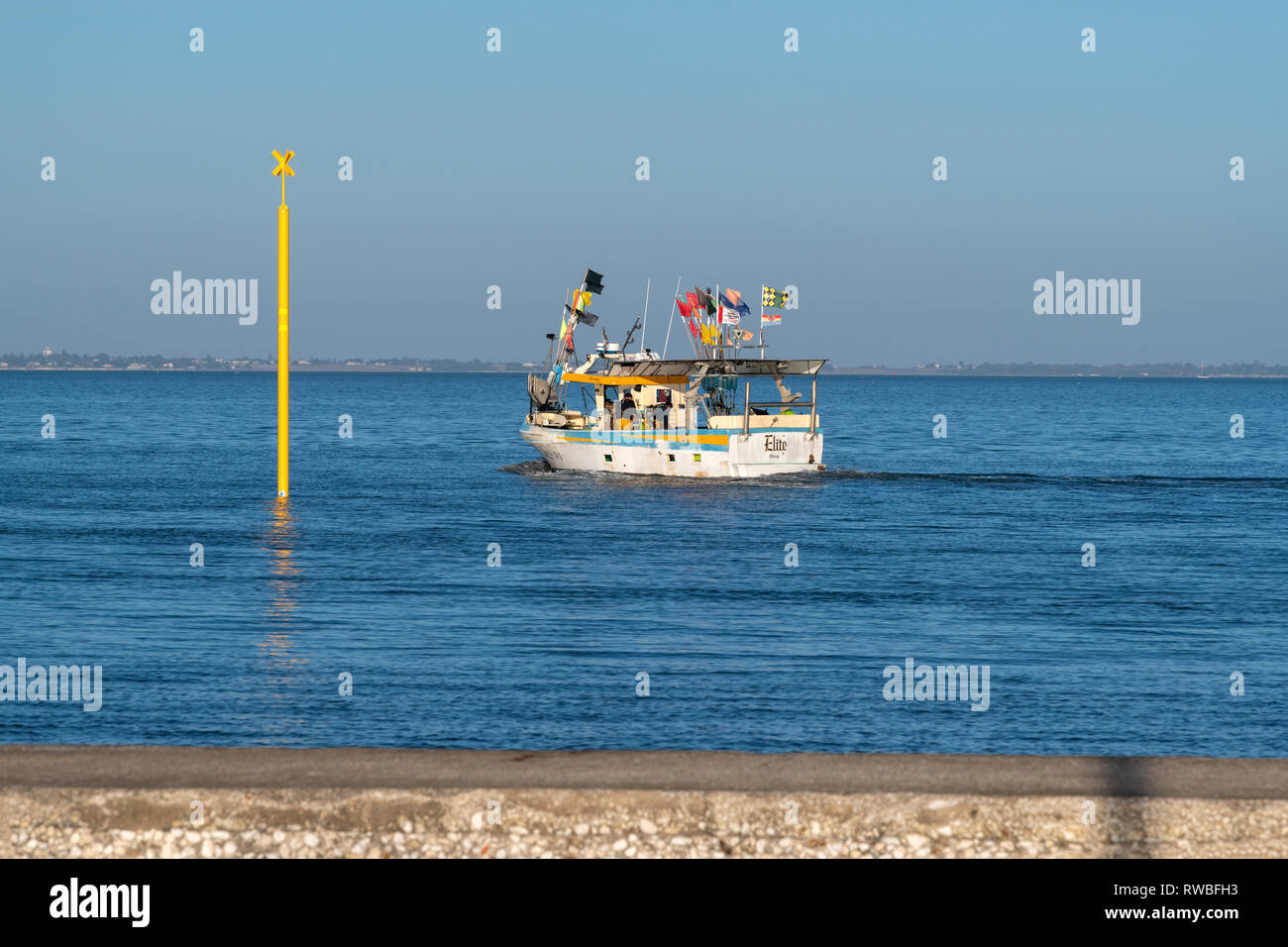 France, 2018, Small trawler navigates around a yellow, waterway marker ...