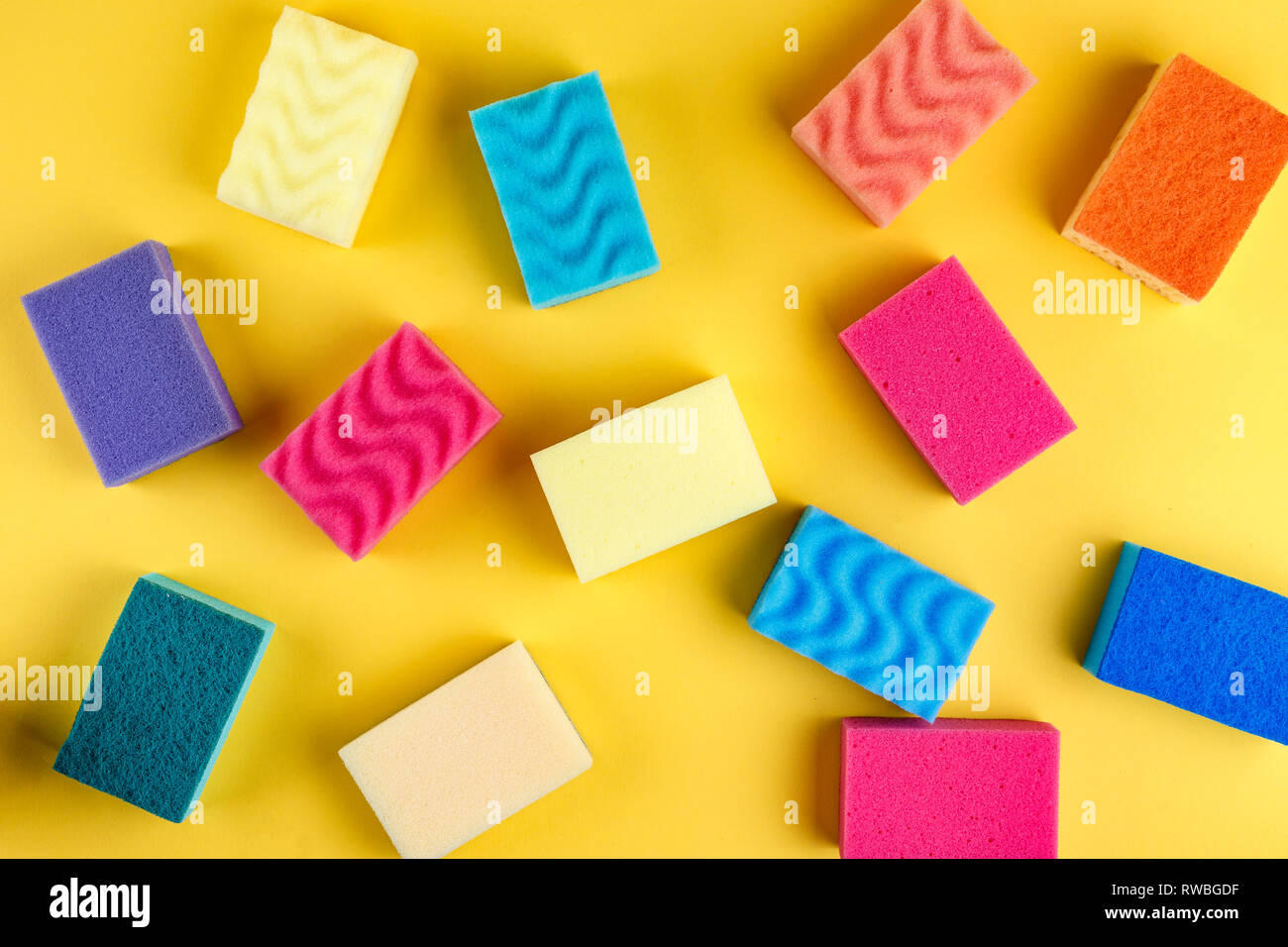 Many multicolored sponge for washing dishes on a yellow background ...