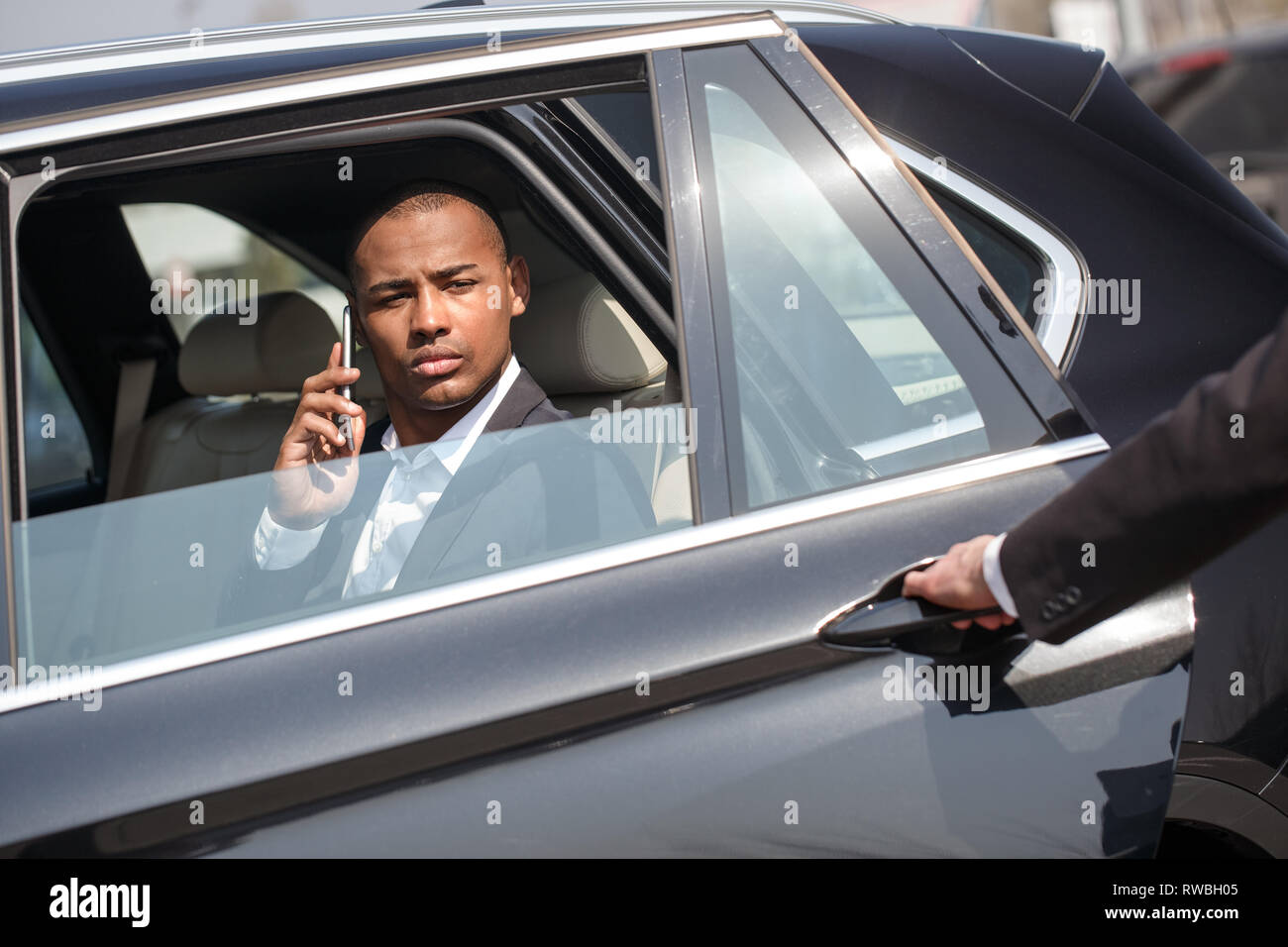 Security guard opening door young mulatto businessman sitting in the ...