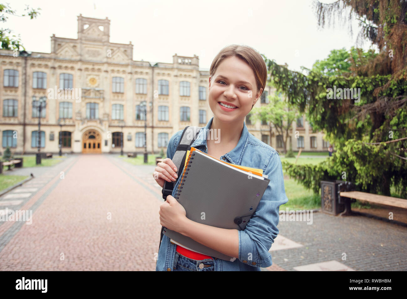 Young female student carrying backpack at university campus walking ...