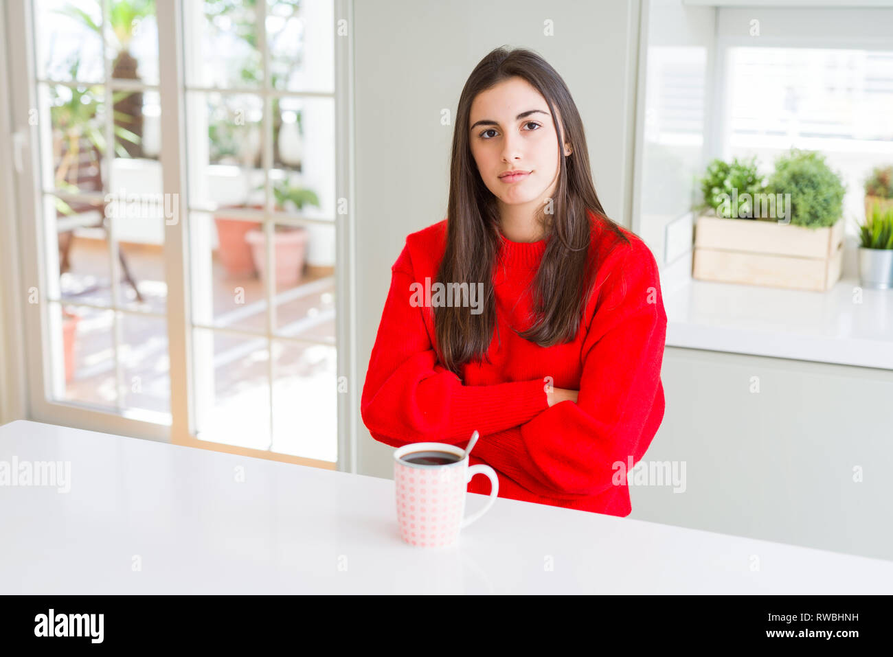 Beautiful young woman drinking a cup of black coffee skeptic and ...