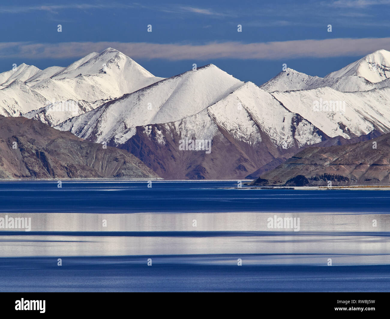 Lake Pangong, blue calm water with white mountain stripes, blue sky ...