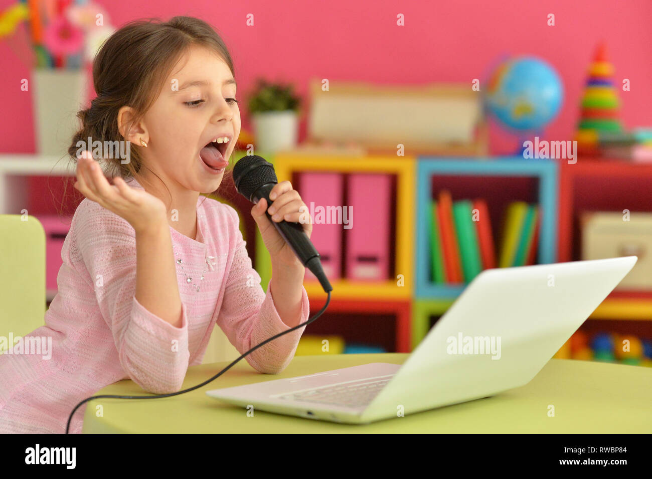 Portrait of adorable little girl using modern laptop and singing ...