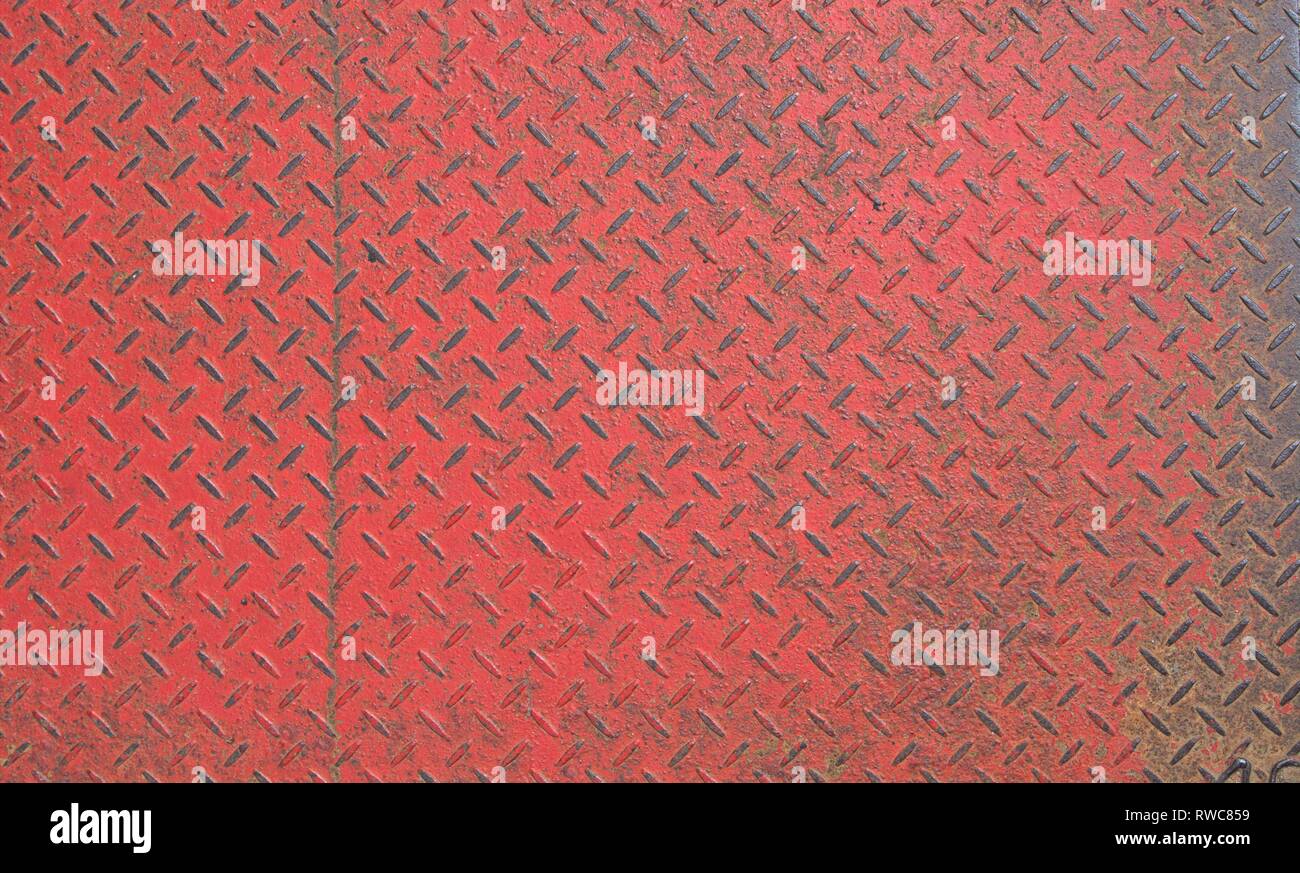 A red checker plate with chipped red paint in detail as background ...