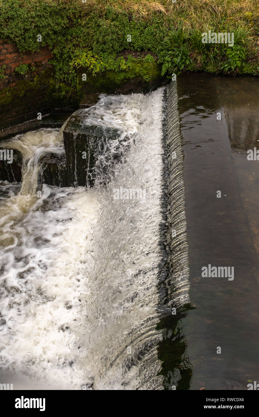 A close up of a stream flowing over a small man made weir on the ...