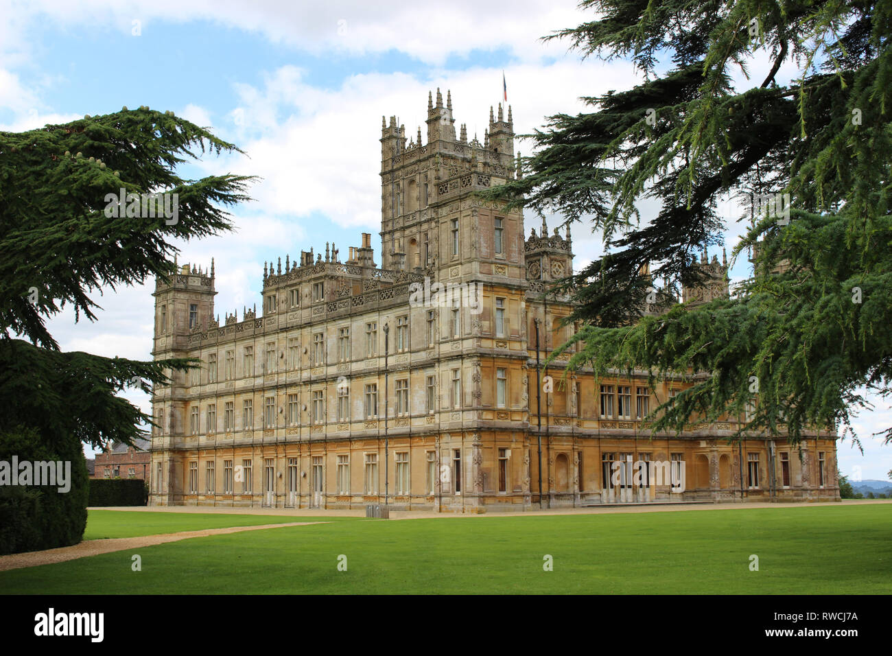 View of Highclere Castle, framed by evergreen trees Stock Photo - Alamy