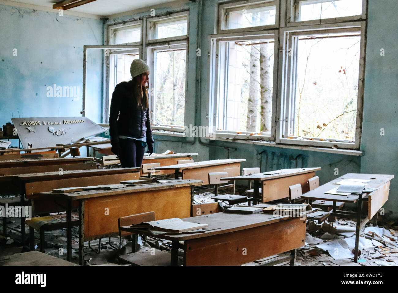 Woman walks through a classroom that was abandoned long ago in wake of ...