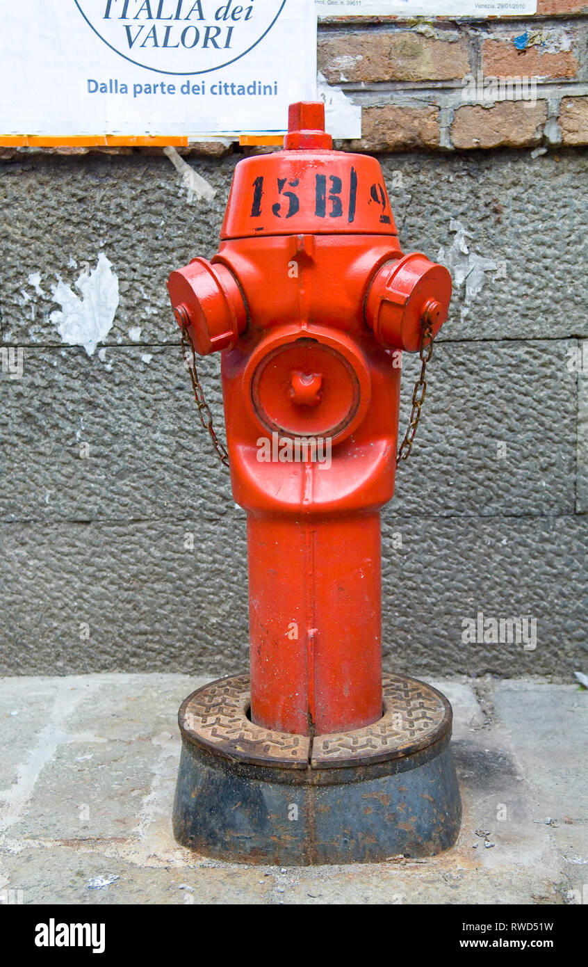A red fire hydrant in Venice, Italy with fly posters in the background ...