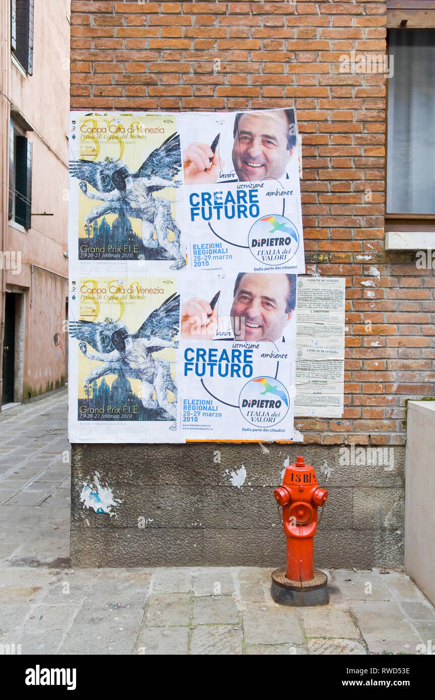 A red fire hydrant in Venice, Italy with fly posters in the background ...