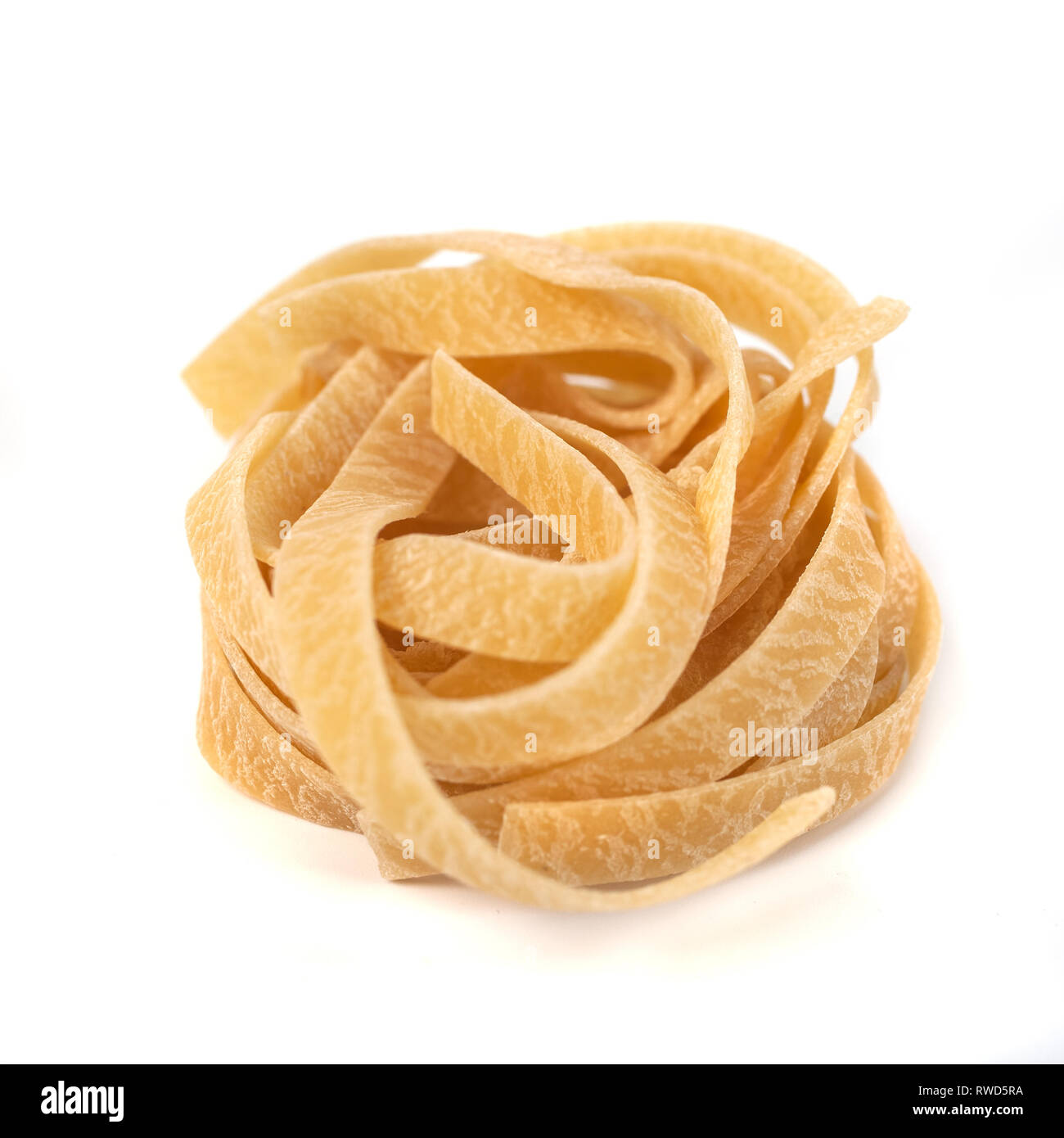 Uncooked nest of tagliatelle Italian pasta isolated on white background ...