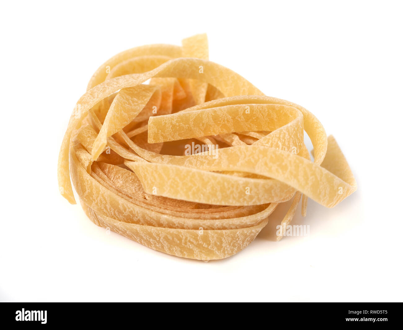 Uncooked nest of tagliatelle Italian pasta isolated on white background ...