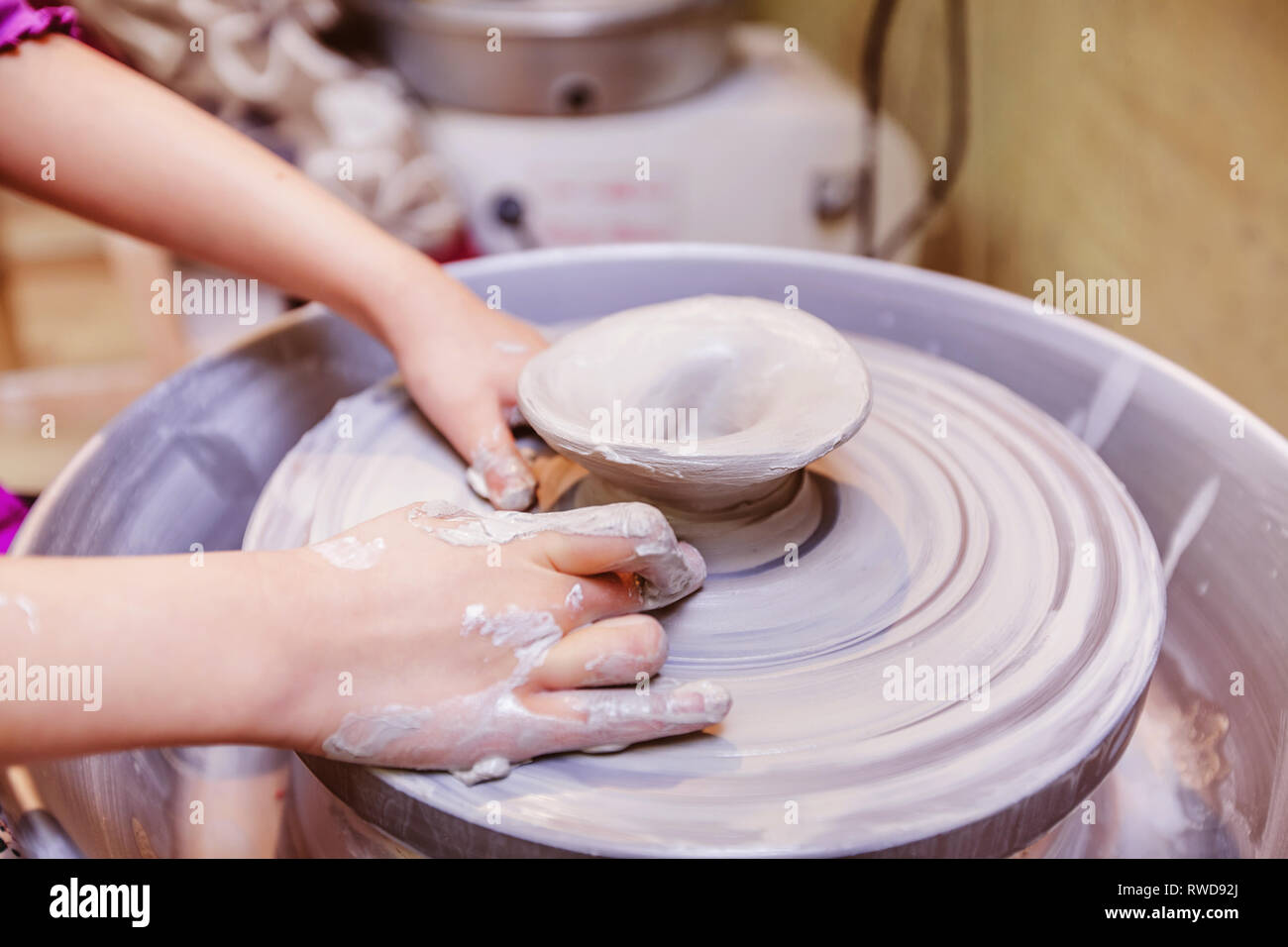 hands of young artist shaping clay on pottery wheel at workshop in ...