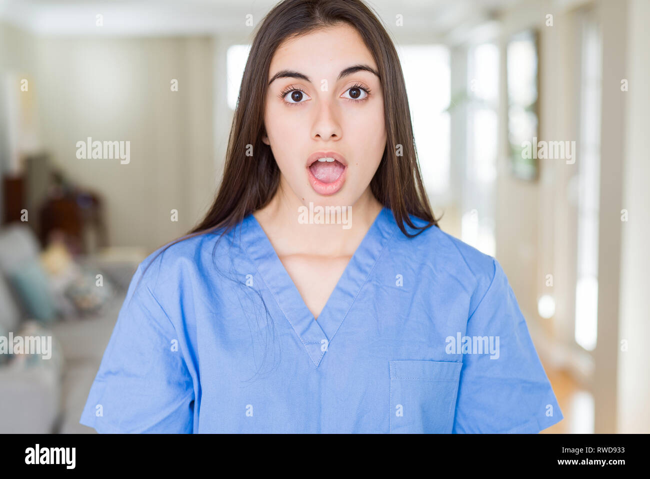 Beautiful young nurse woman at the clinic afraid and shocked with ...