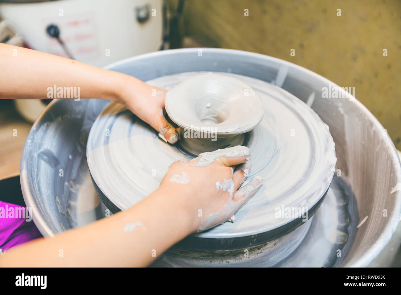 hands of young artist shaping clay on pottery wheel at workshop in ...