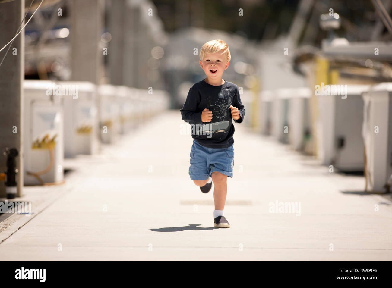 Boy having fun running down the boardwalk of a marina Stock Photo - Alamy
