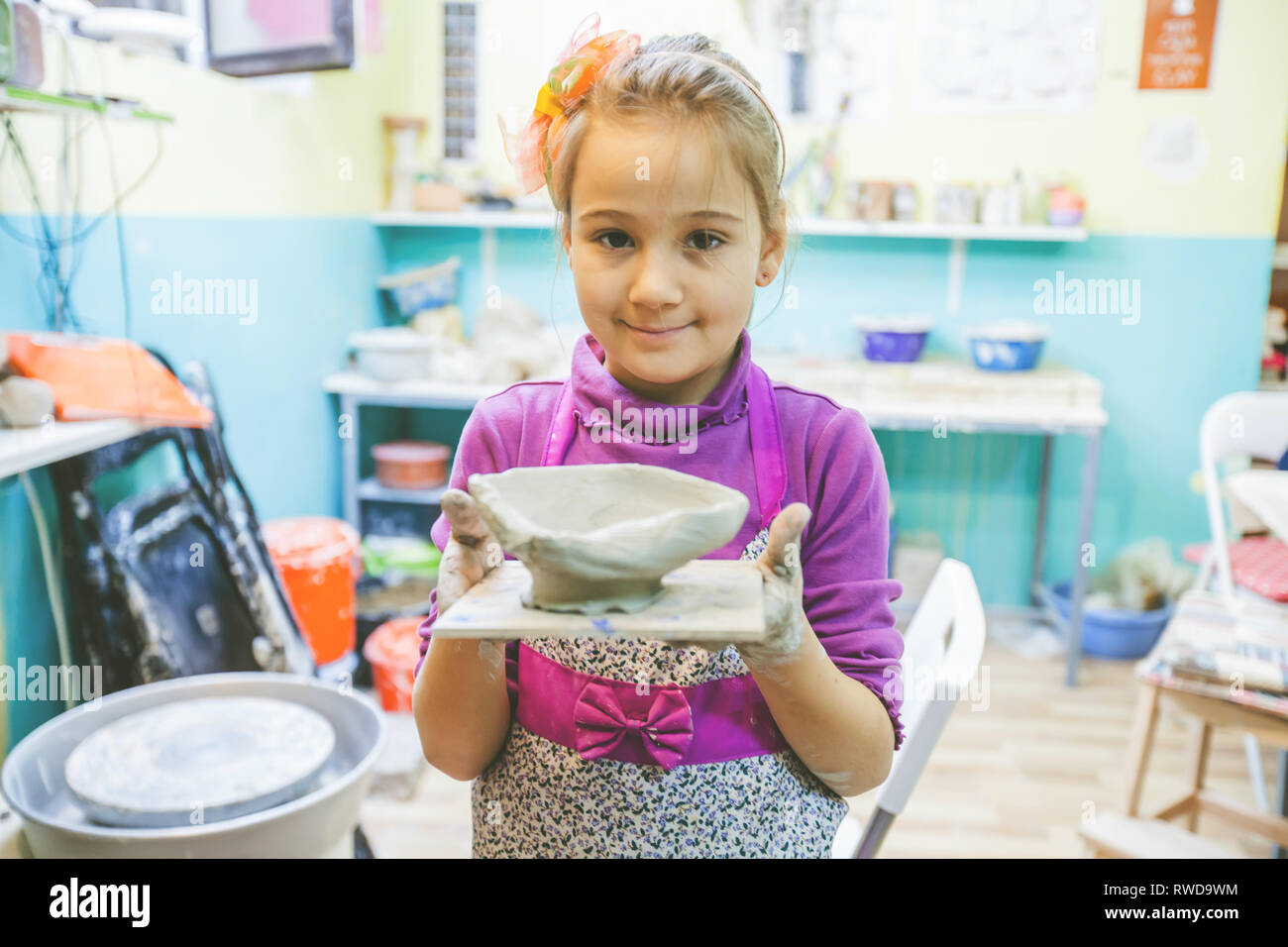Portrait of little artist at pottery class shows clay vase in ceramic ...