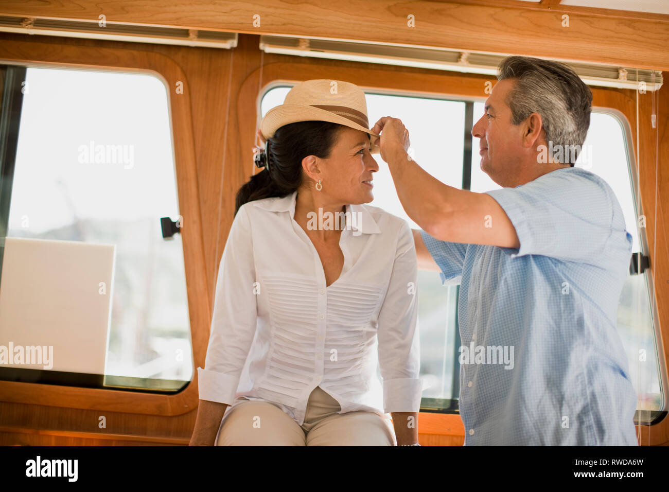 Husband putting his hat on his wife as they sit in a boat Stock Photo ...