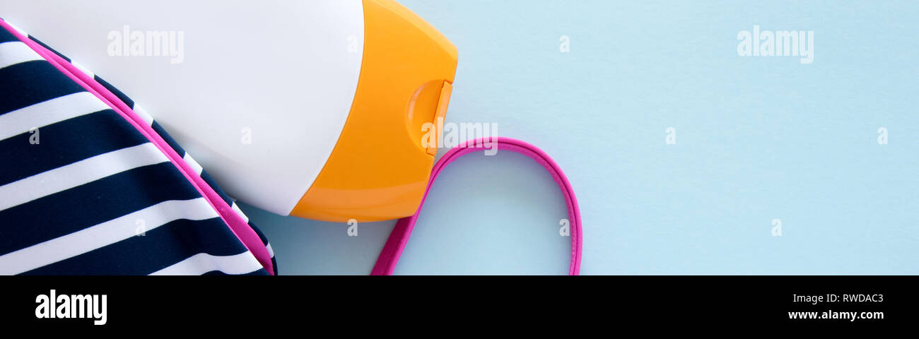 Beach items - swimwear and sun protection cream on light blue ...