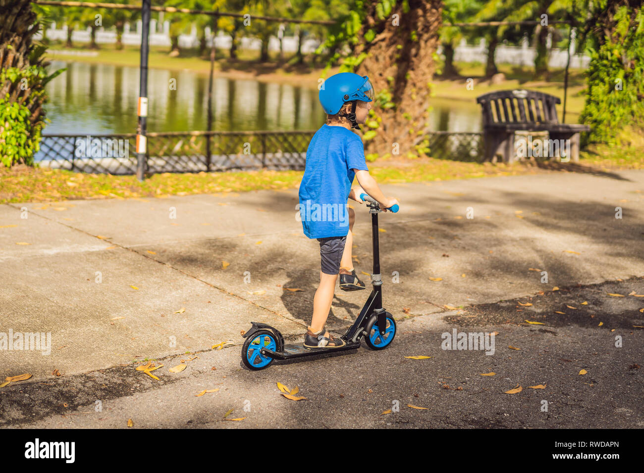 Boy riding scooters, outdoor in the park, summertime. Kids are happy ...
