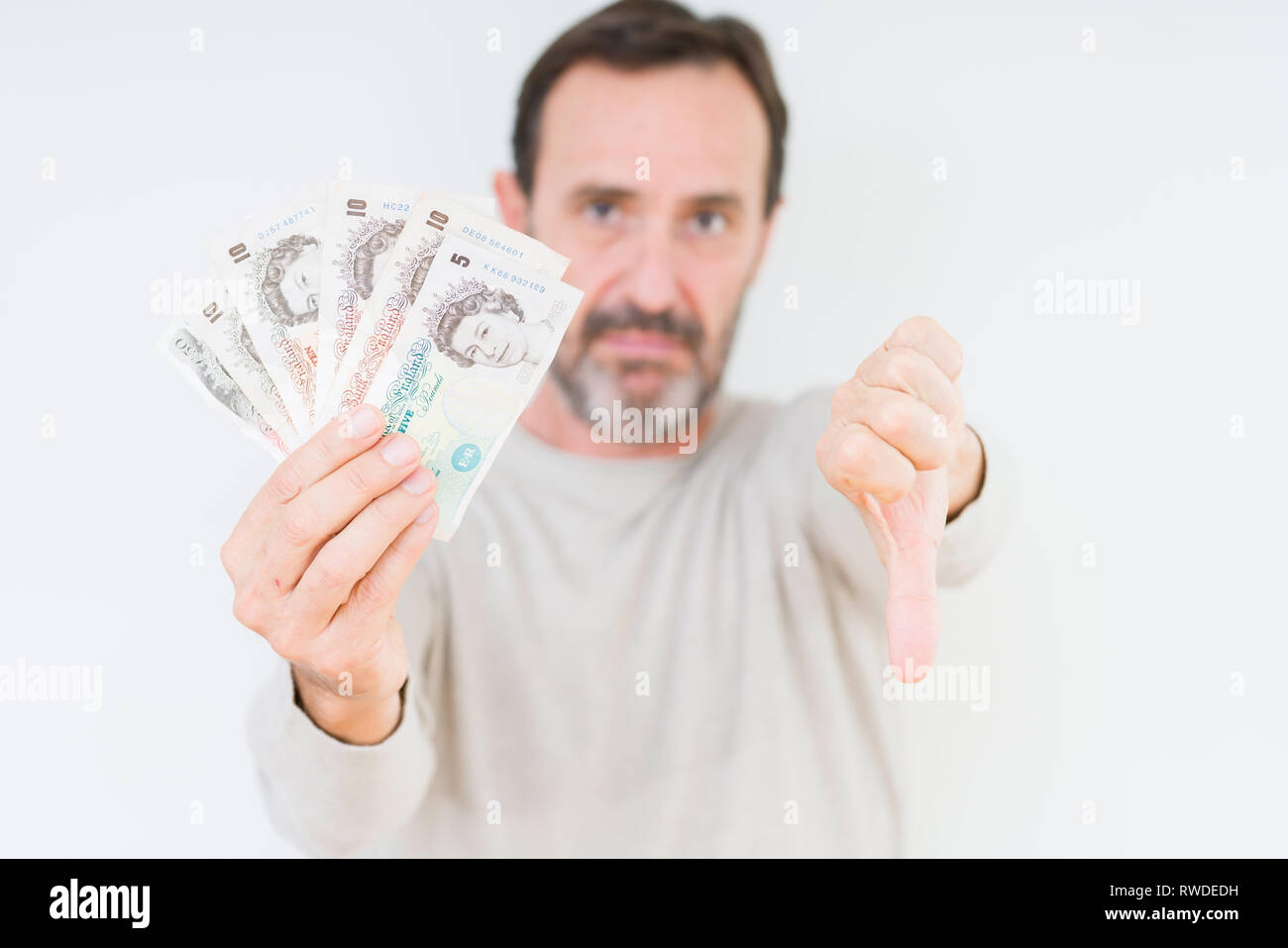Senior man holding bunch of pounds bank note over isolated background ...