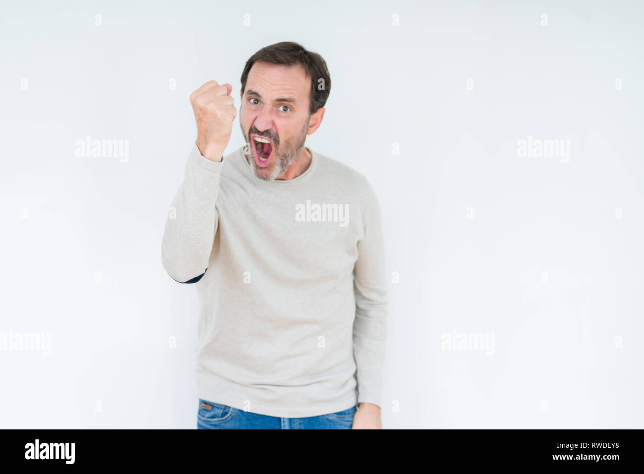 Elegant senior man over isolated background angry and mad raising fist ...
