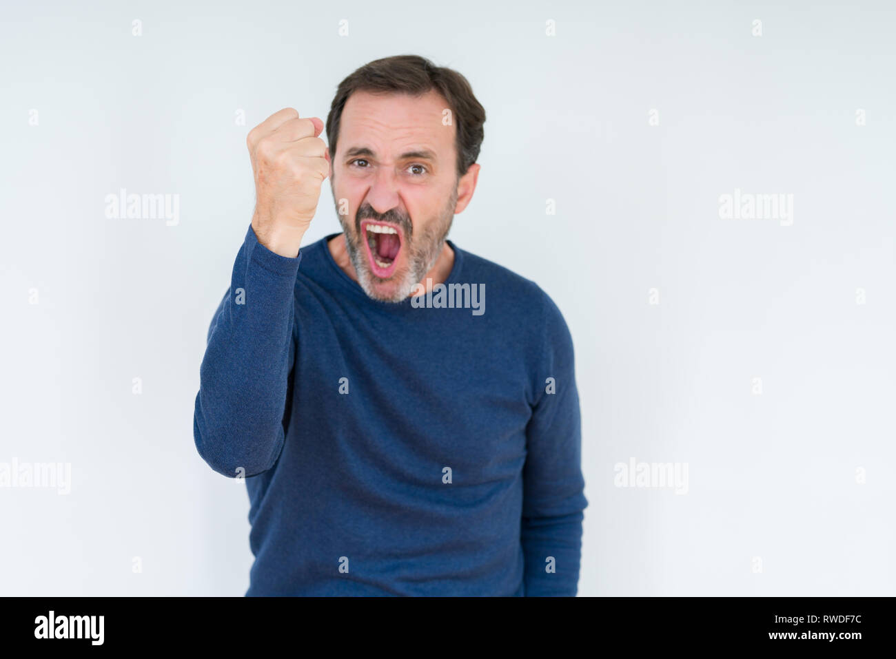 Elegant senior man over isolated background angry and mad raising fist ...