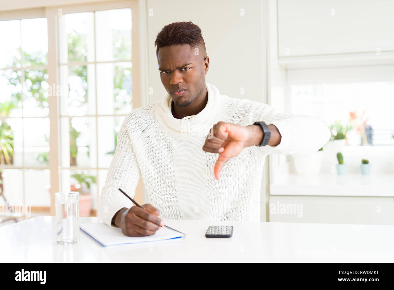 African american student man writing on a paper using a pencil with ...