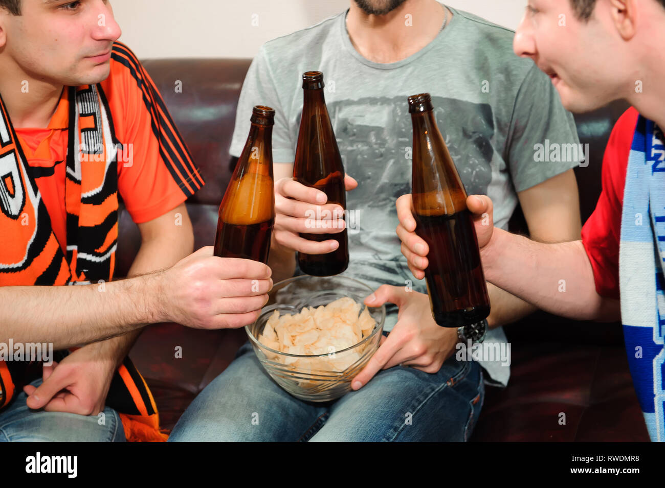 Friends cheering and drinking alcohol while watching soccer match on TV ...