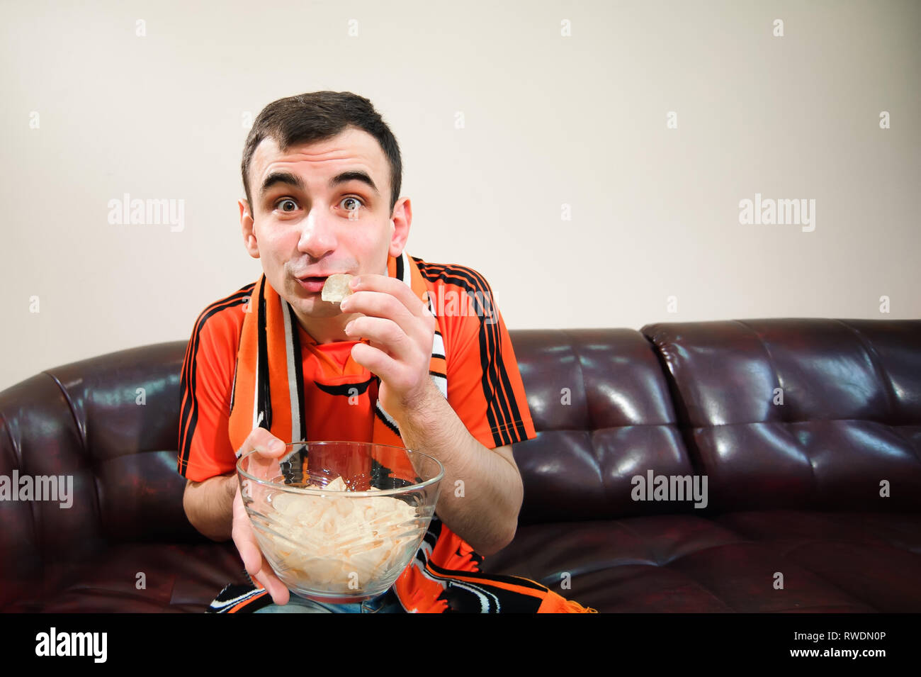Man watching football and eating chips, football fan Stock Photo - Alamy