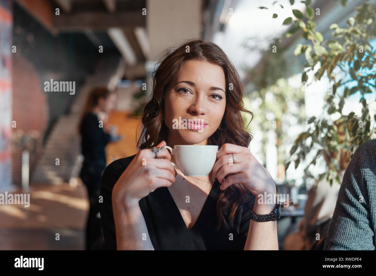 Attractive young woman drinking tea at lunch break from white cup and ...