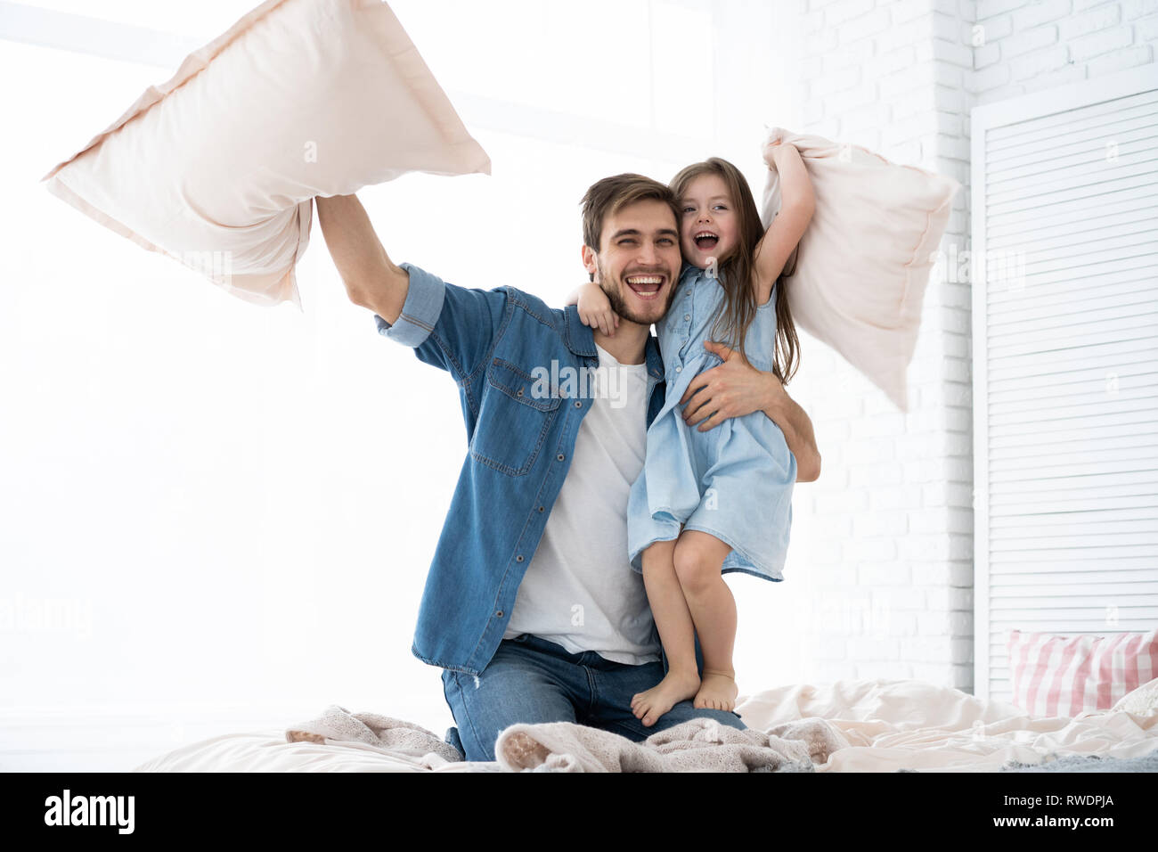 happy father and daughter playing pillow fight in bed at morning Stock ...