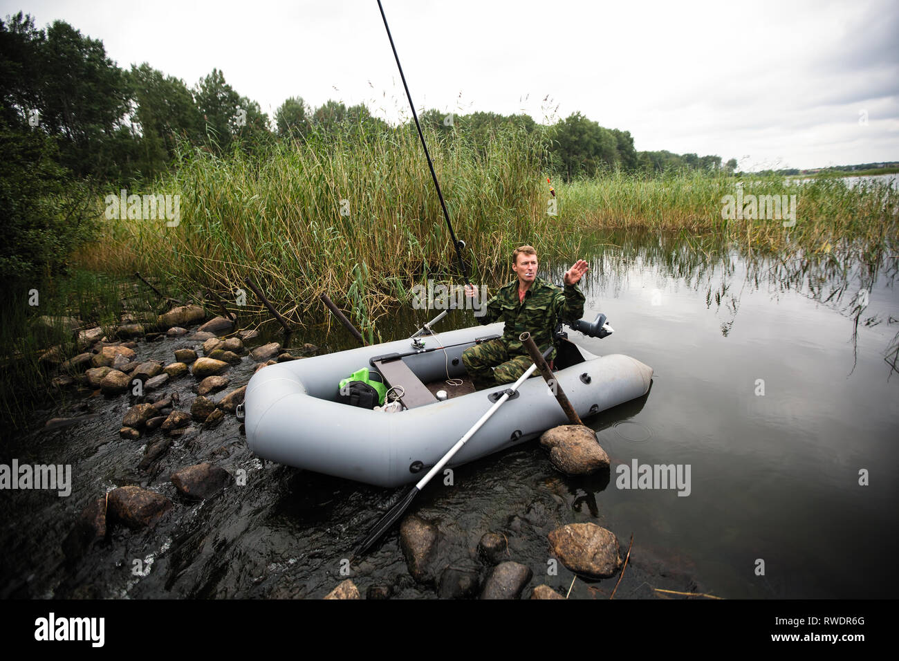 Fisherman on rubber boat catching fish on the river Stock Photo - Alamy