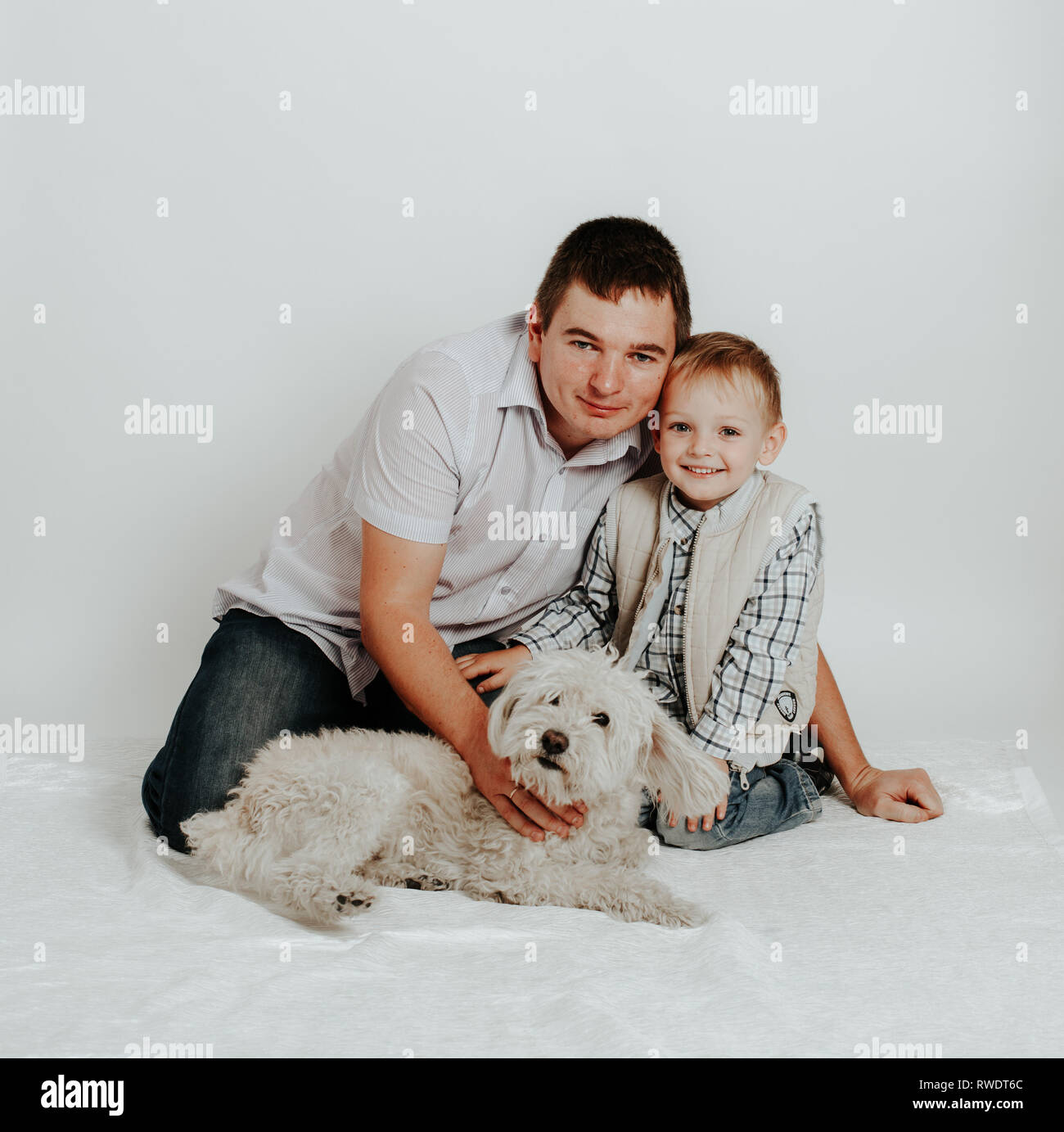 Family father and boy sit with dog on white background Stock Photo - Alamy